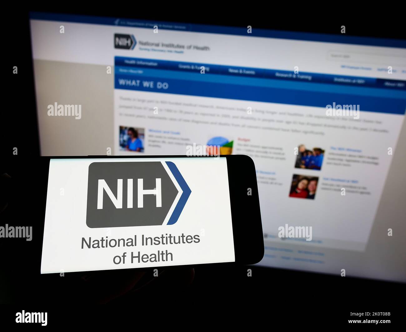 Person holding mobile phone with logo of US agency National Institutes ...