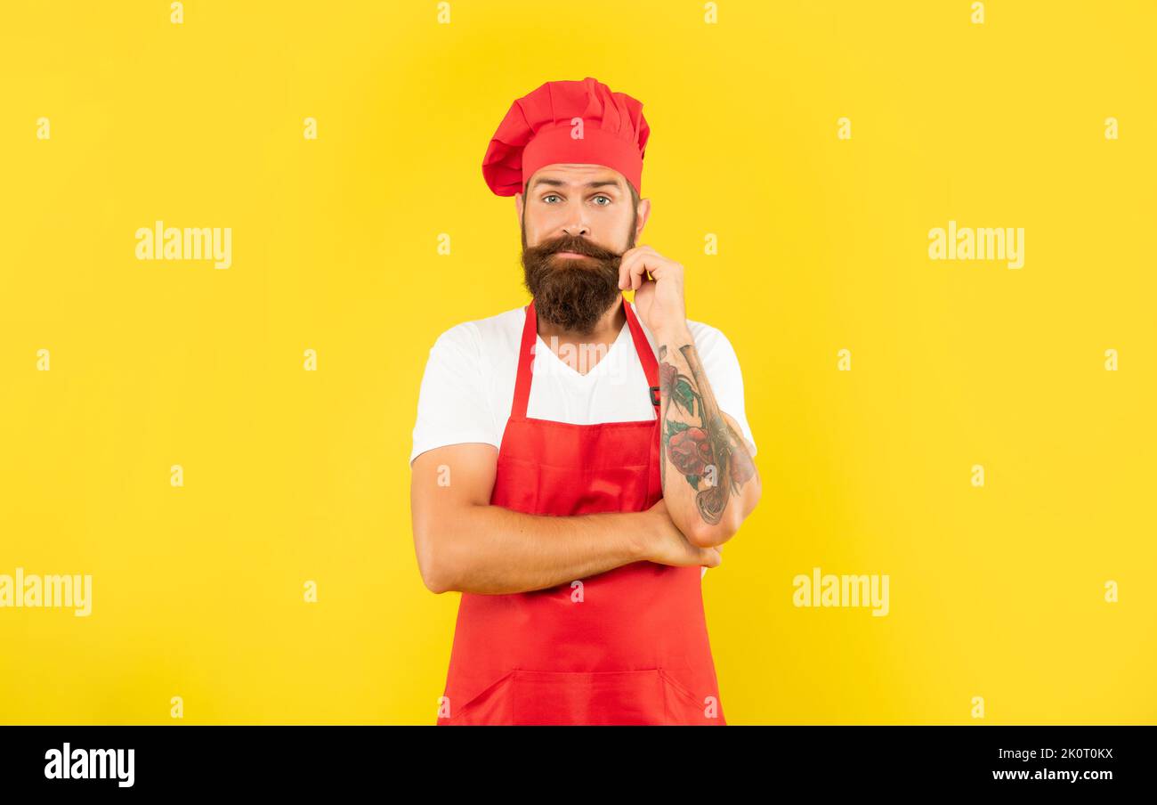 Man in red apron and toque twirling moustache with puzzled look yellow ...