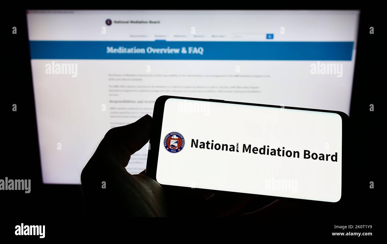 Person holding cellphone with logo of US agency National Mediation ...