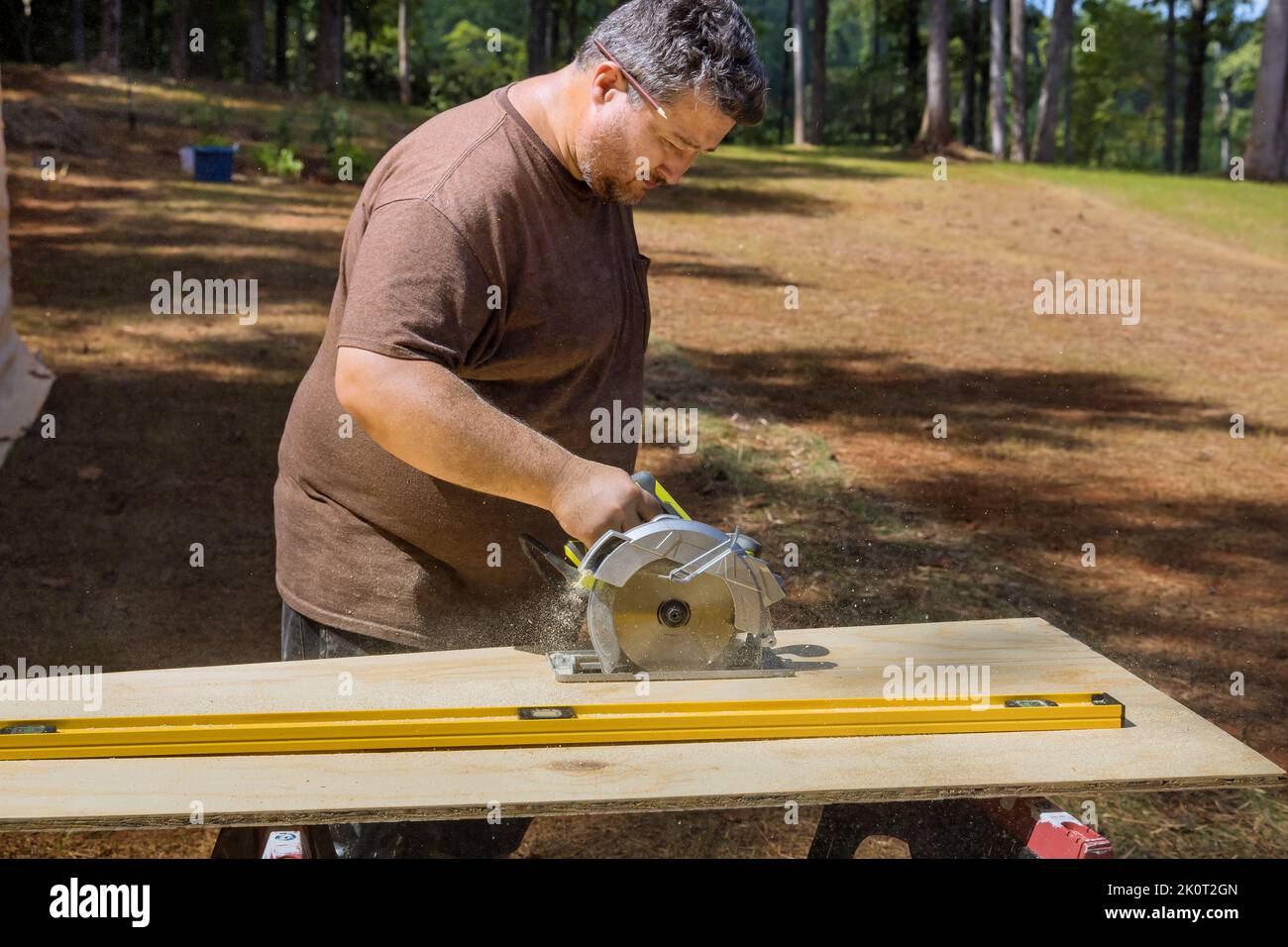 Worker using a circular saw to cut plywood using a circular saw held in ...