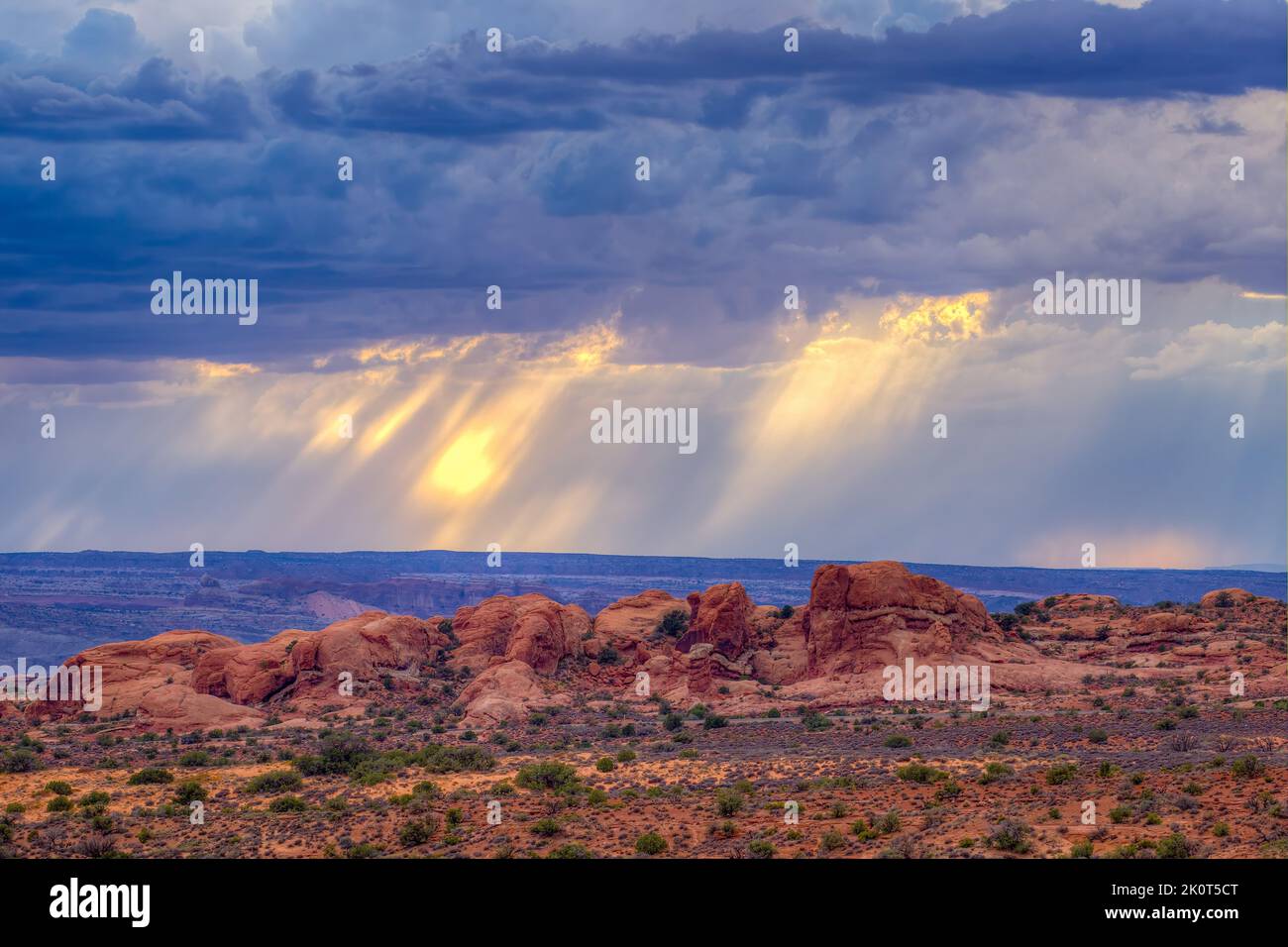 Sun rays through rain clouds over the canyonlands as seen from Arches ...