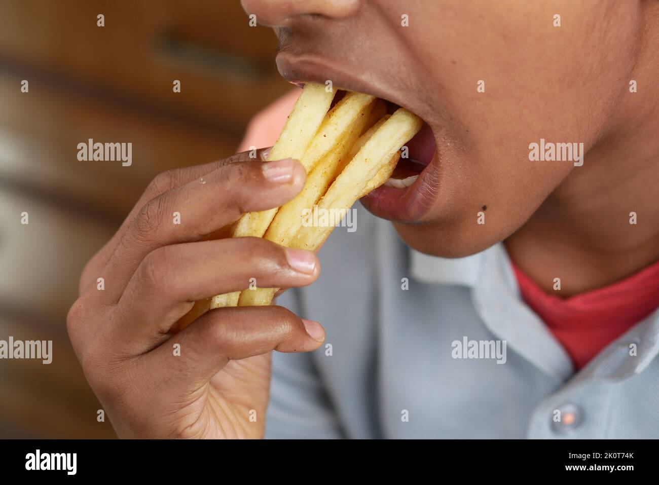 a teenage boy eating french fries while sited Stock Photo - Alamy