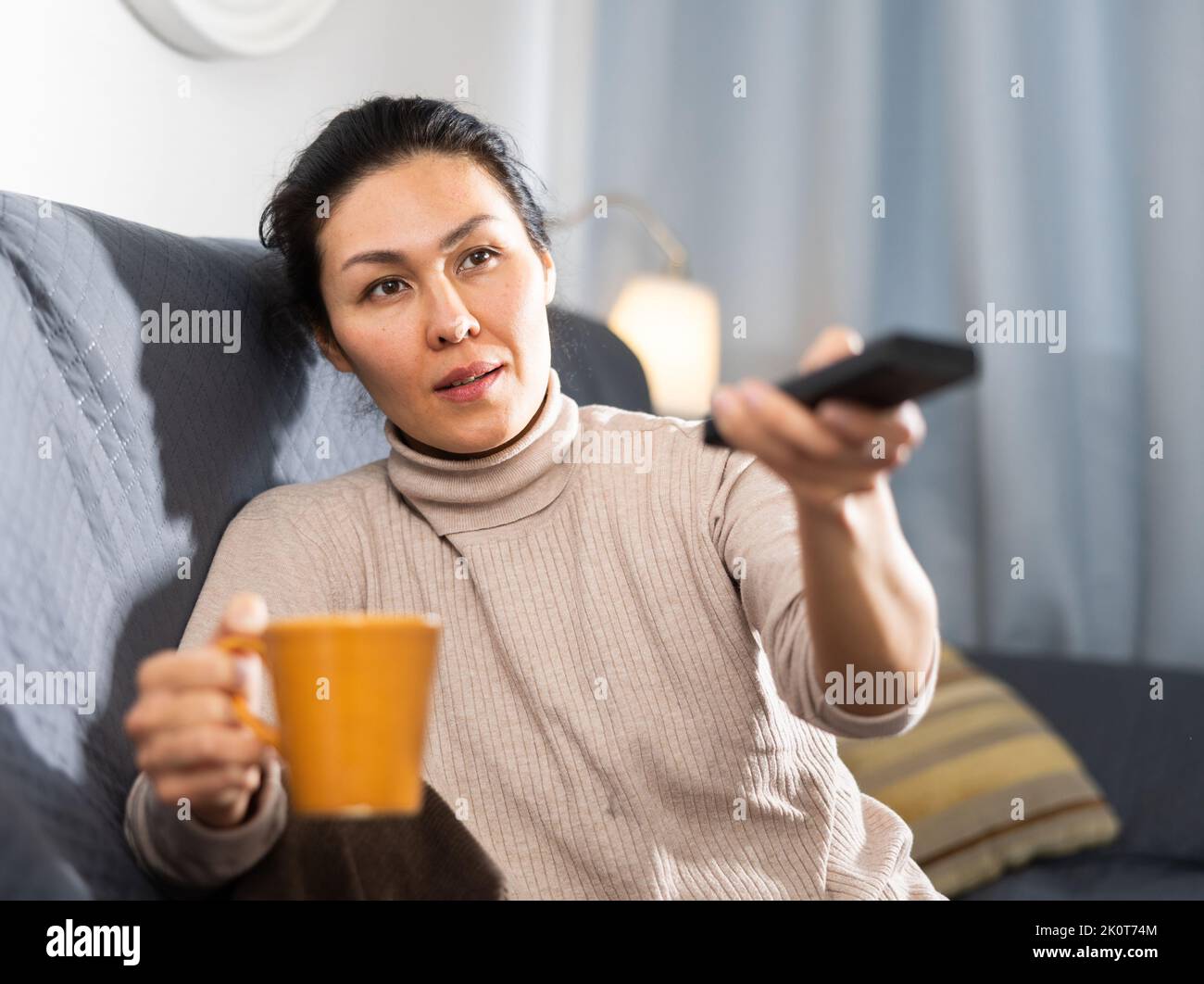Asian woman watching TV Stock Photo - Alamy