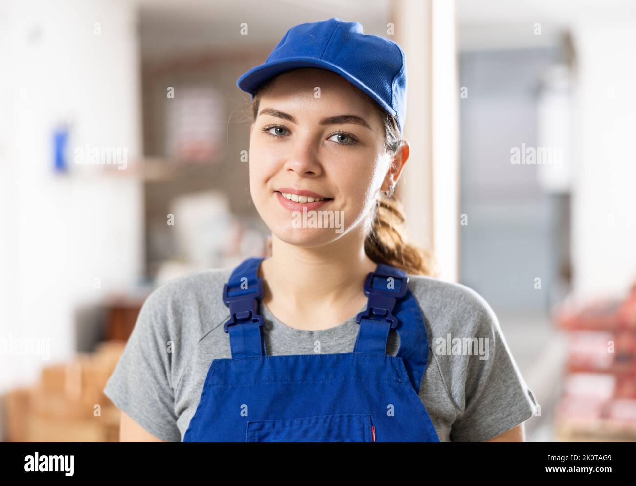 Smiling young female builder in blue uniform at construction site Stock ...
