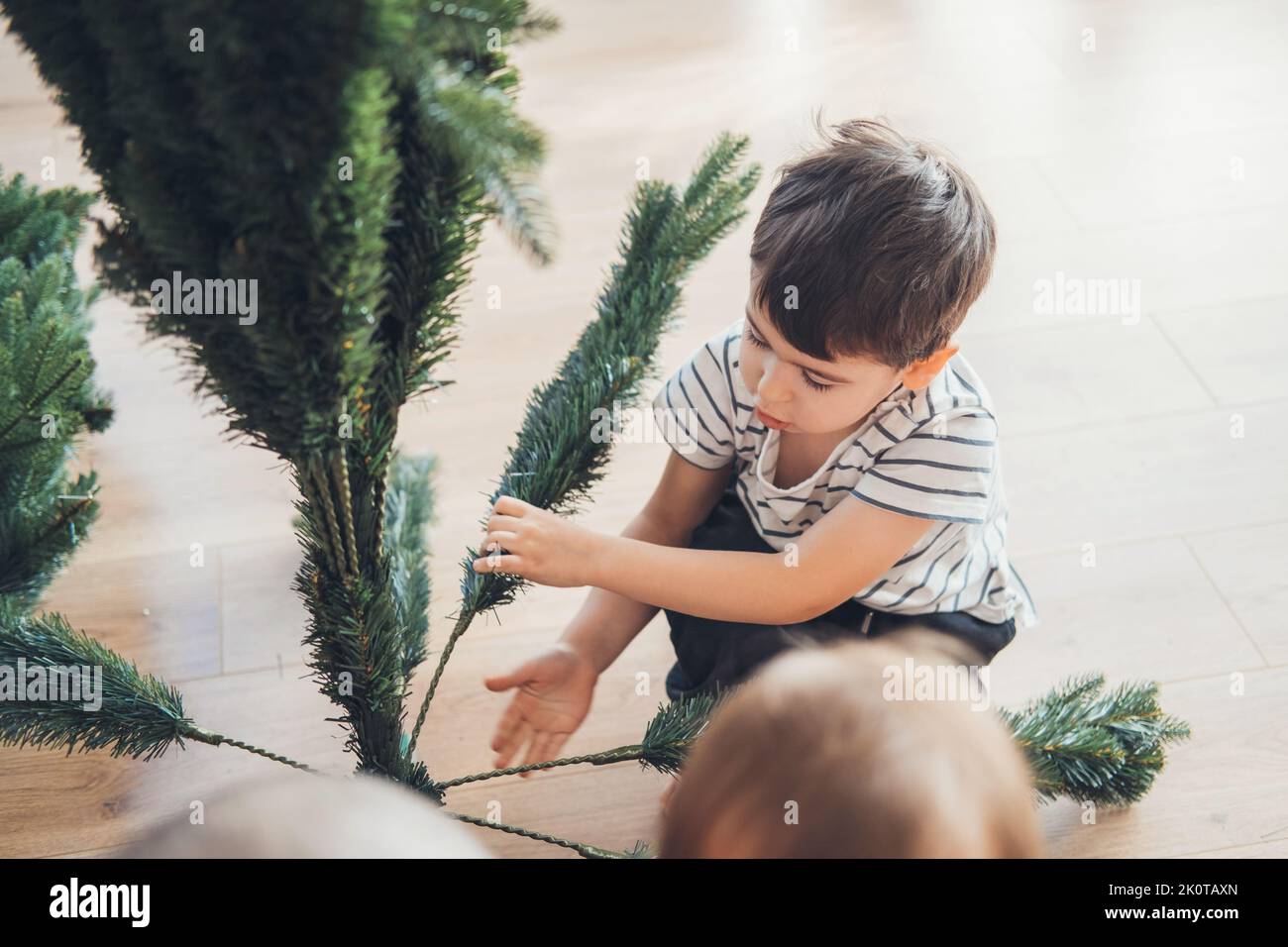 Handsome little boy assembling the Christmas tree in living room ...