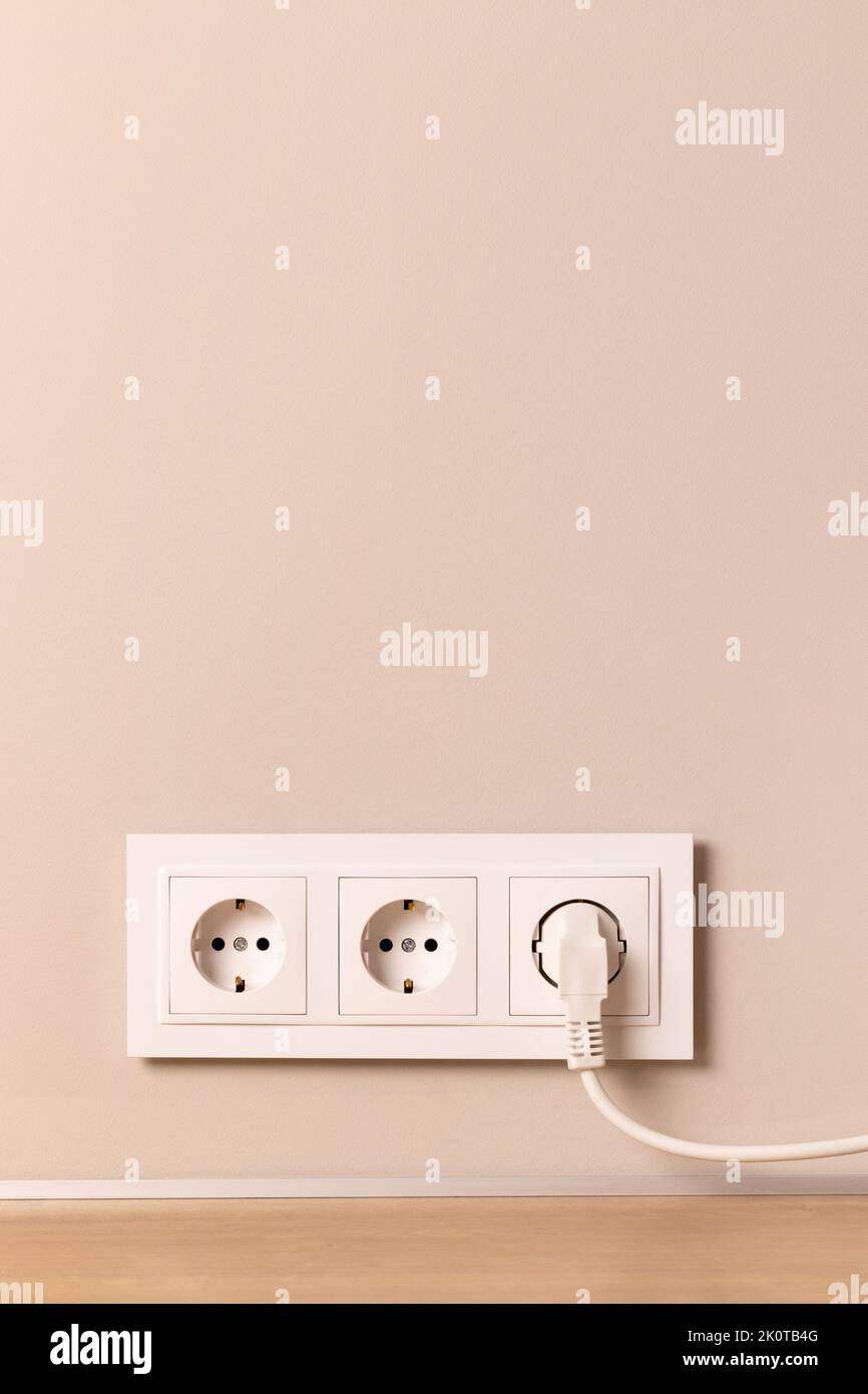 Group of white european electrical outlets with plug inserted into it ...