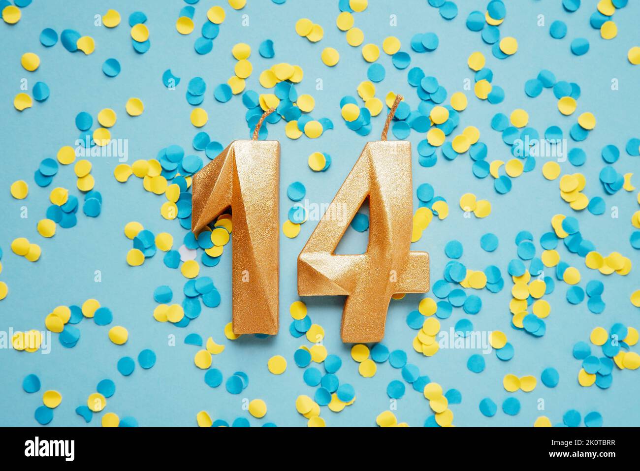 Number 14 fourteen golden celebration birthday candle on yellow and ...