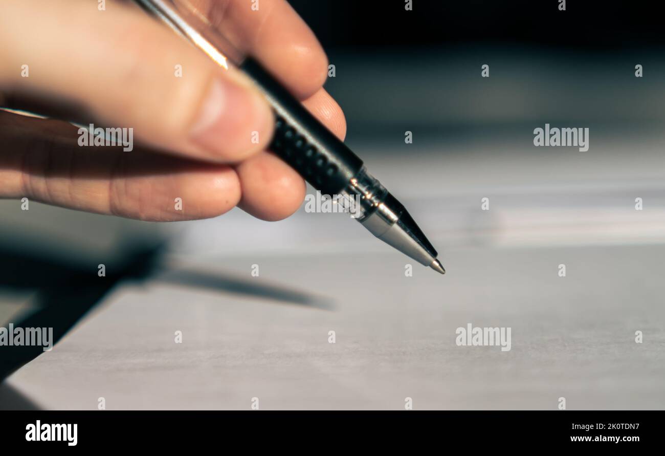 Close up view of a person about to sign an important document in his ...