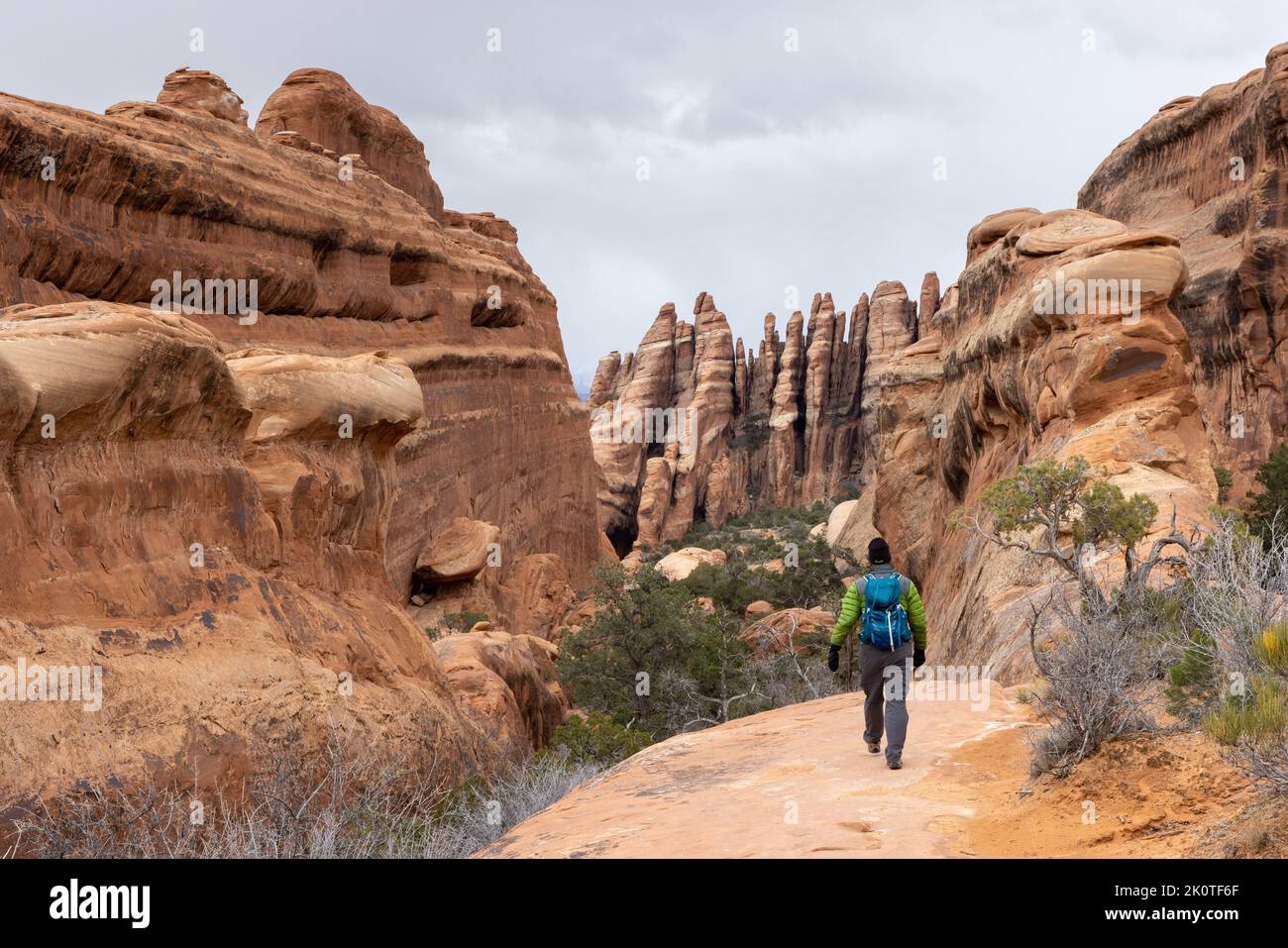 A male hiker descending on top of sandstone between two larger ...
