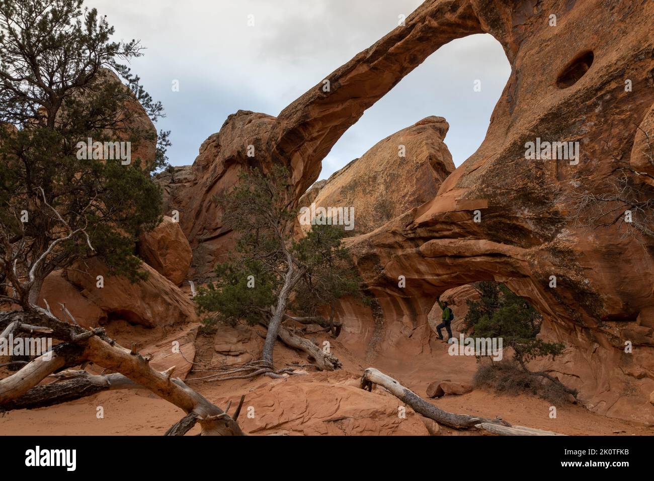 A male hiker standing in the lower arch of Double O Arch in the Devils ...