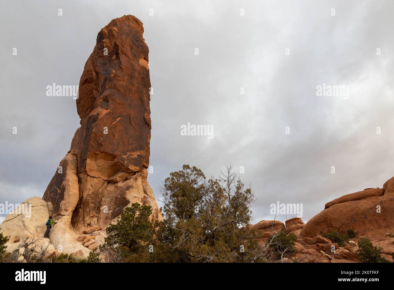A male hiker standing at the base of the Dark Angel sandstone spire ...