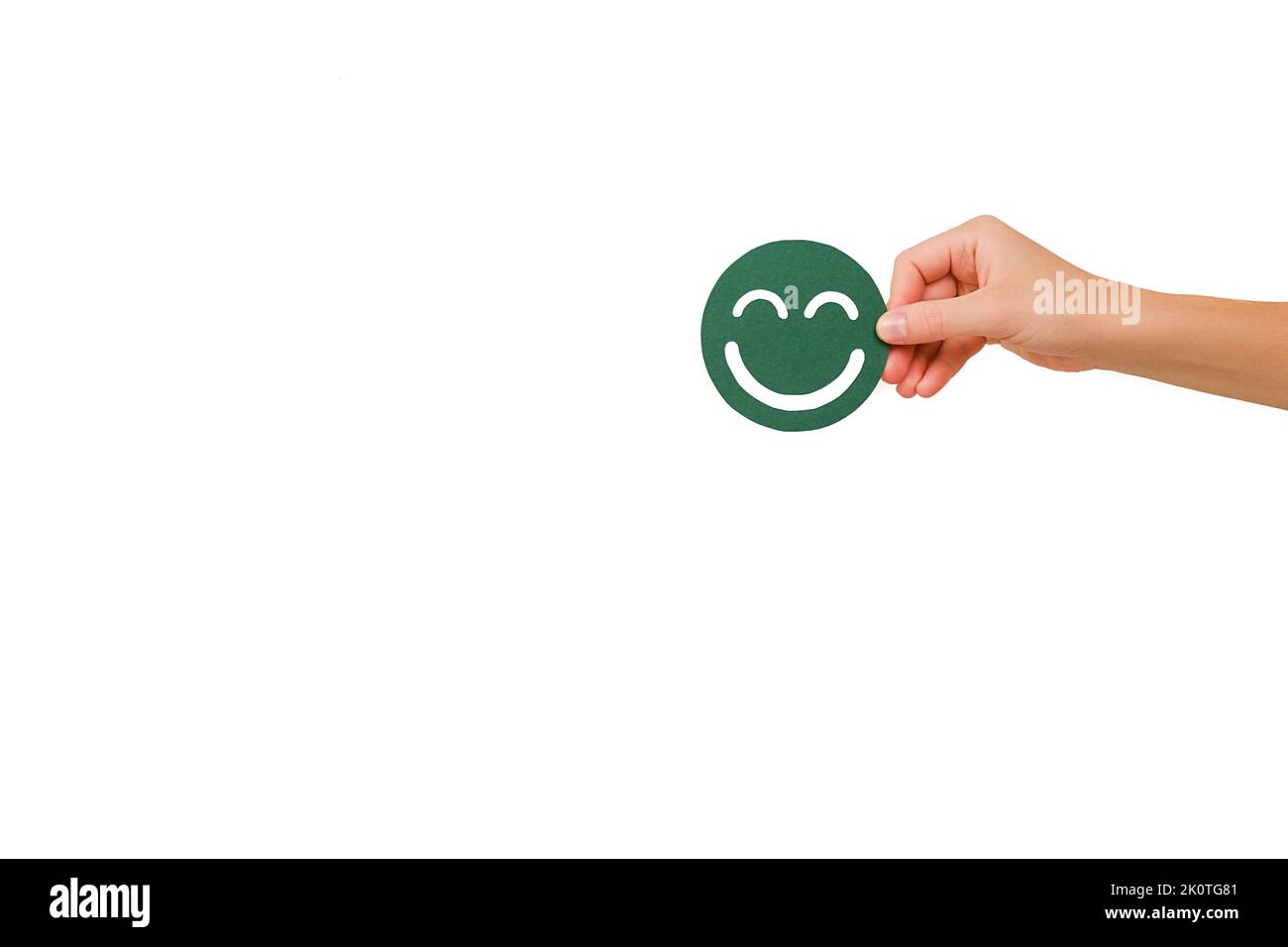 Close up of female hand holding small positive green smiley face ...