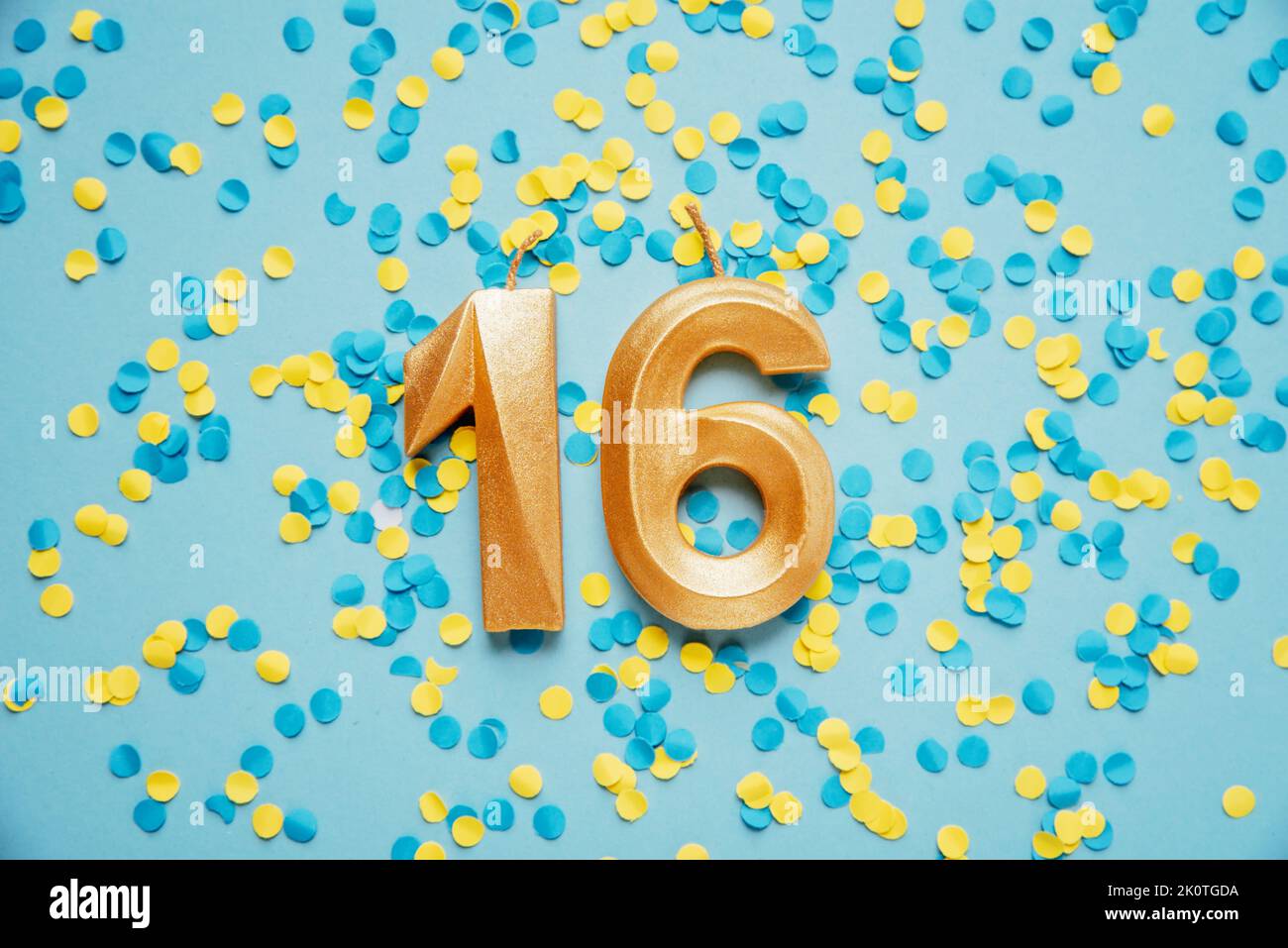 Number 16 sixteen golden celebration birthday candle on yellow and blue ...