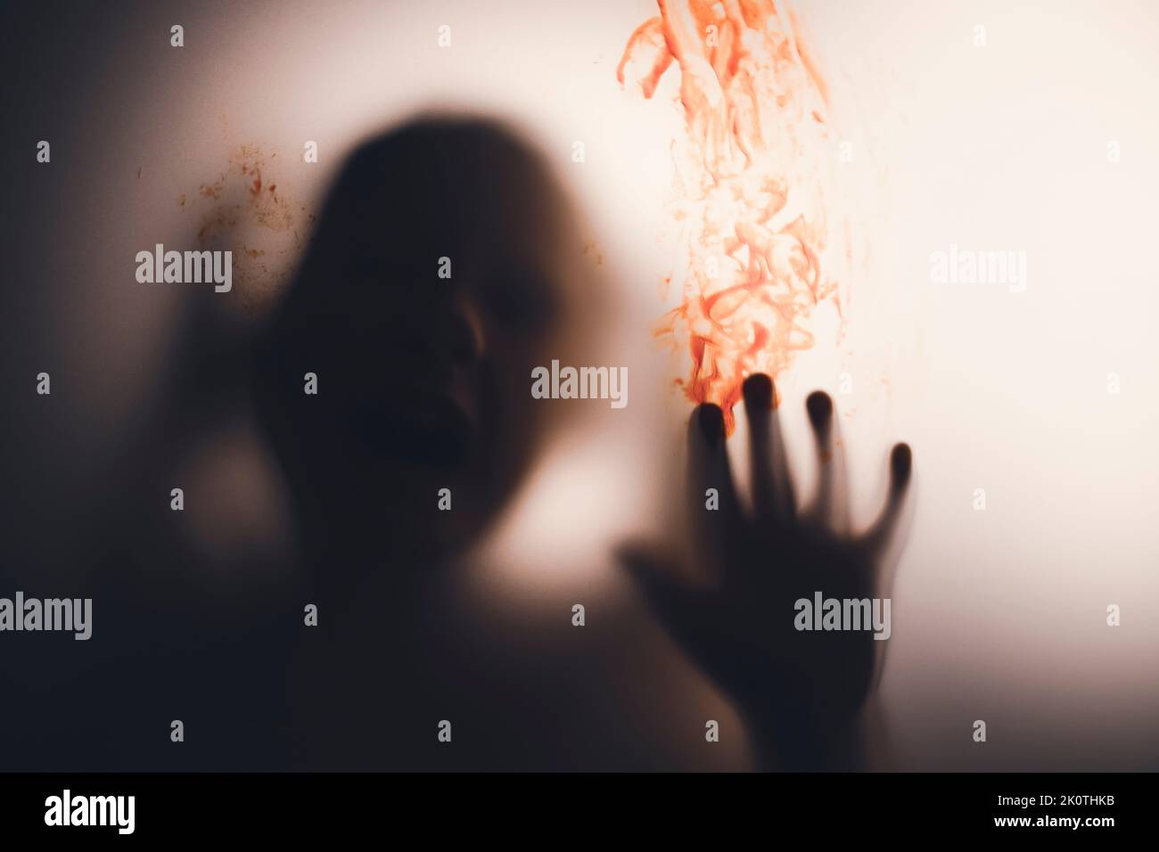 Horror ghost girl with blood on her hand behind the matte glass ...