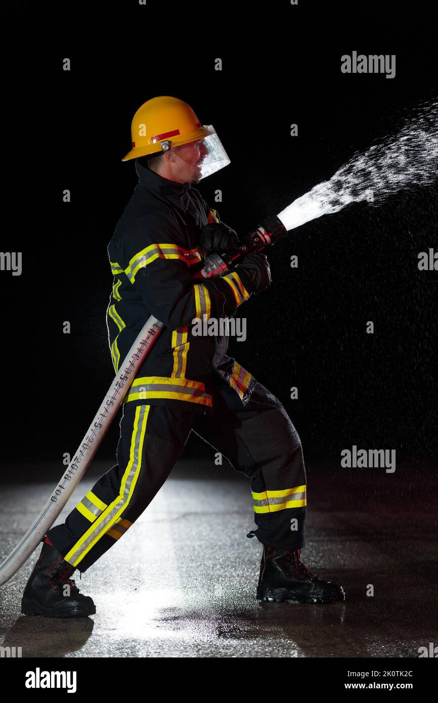 Firefighter in fire fighting operation. Portrait of a heroic fireman in ...