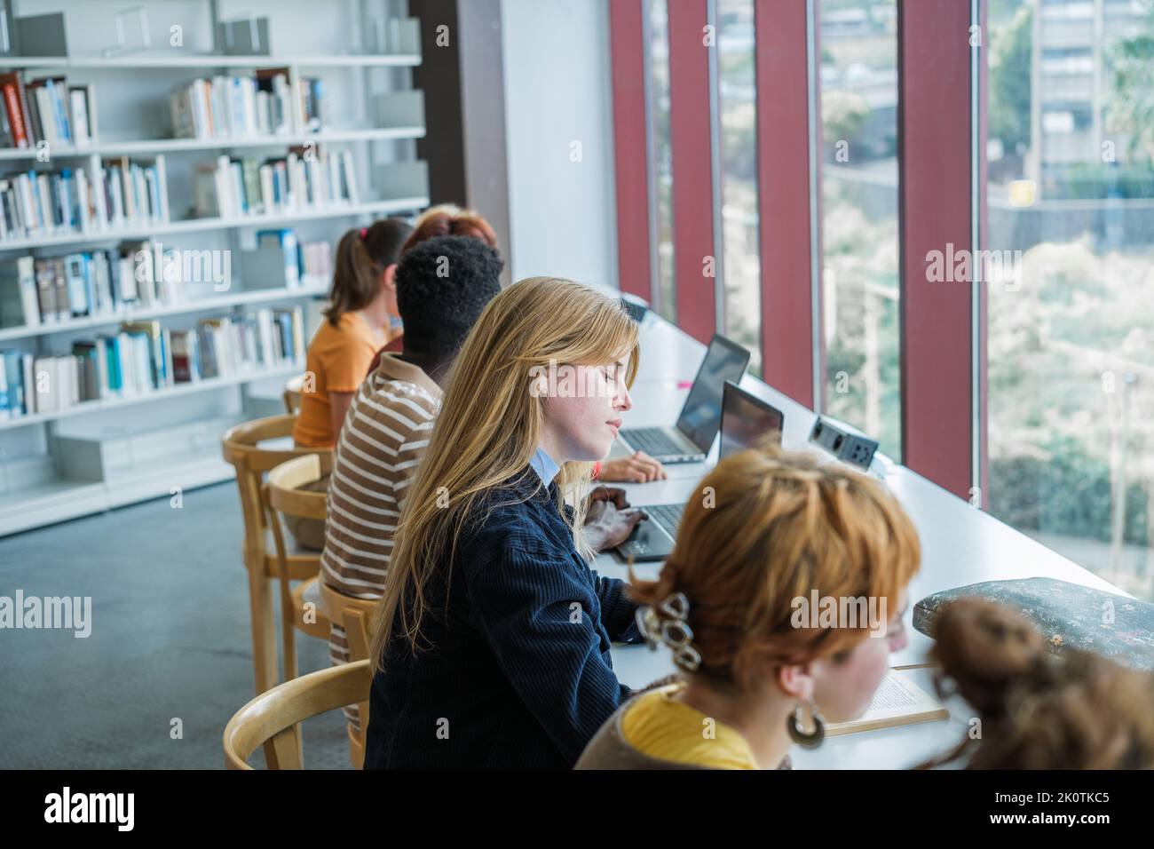 College students studying in the university library in front of a large ...