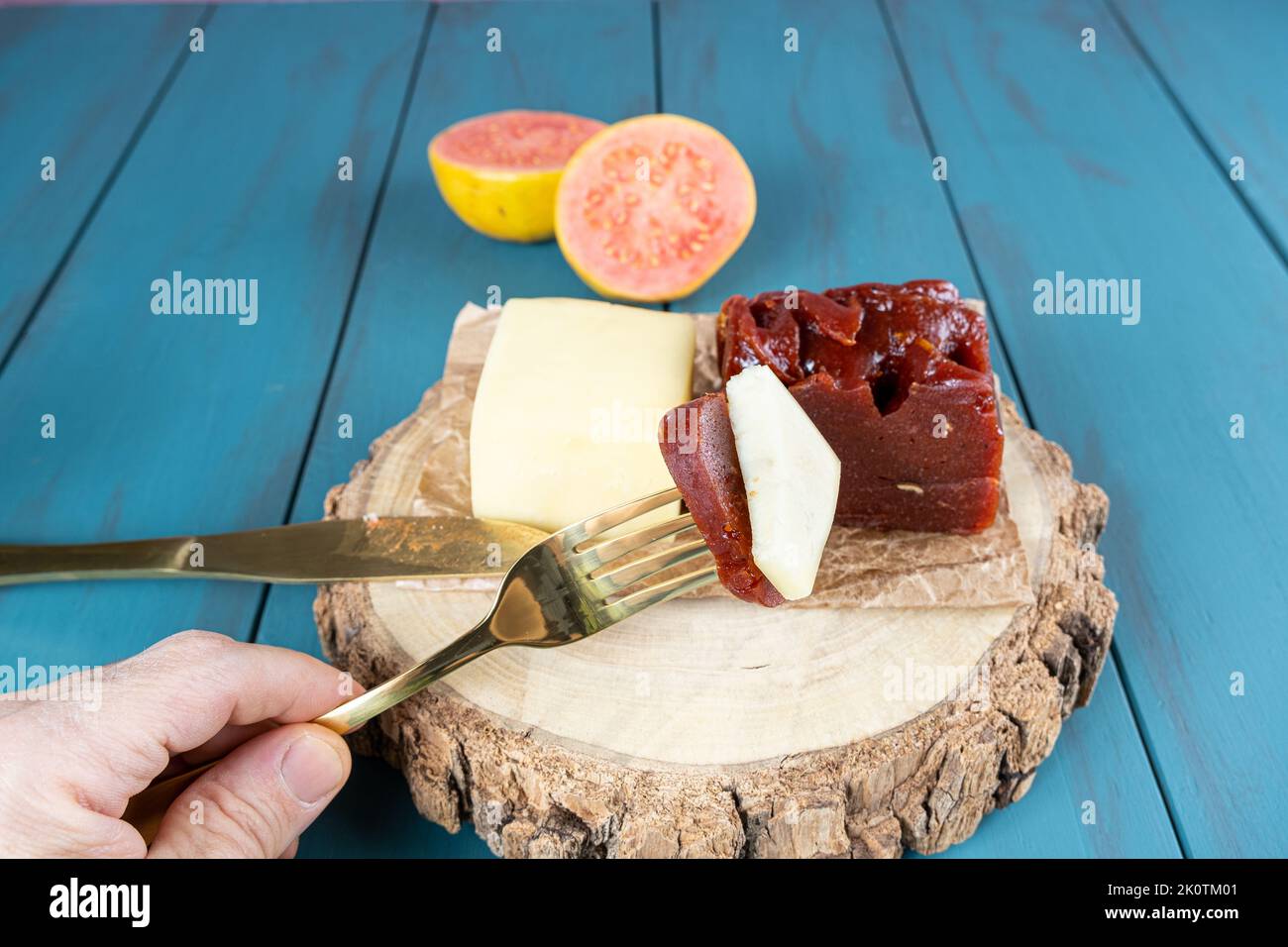 Man holding a fork with pieces of guava sweet with cheese, on a wooden ...