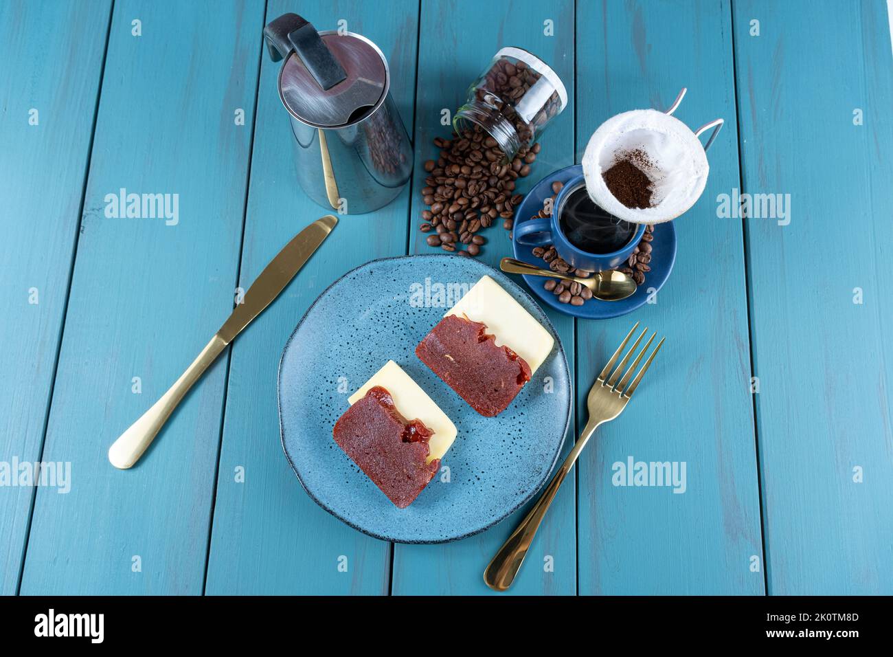 Guava sweet with cheese surrounded by cutlery, cup and coffee beans on ...