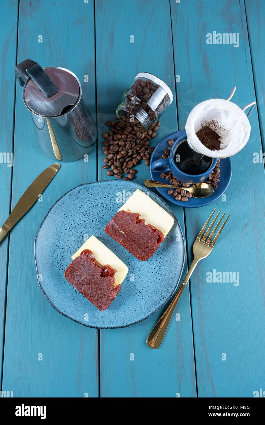 Guava sweet with cheese surrounded by cutlery, cup and coffee beans on ...