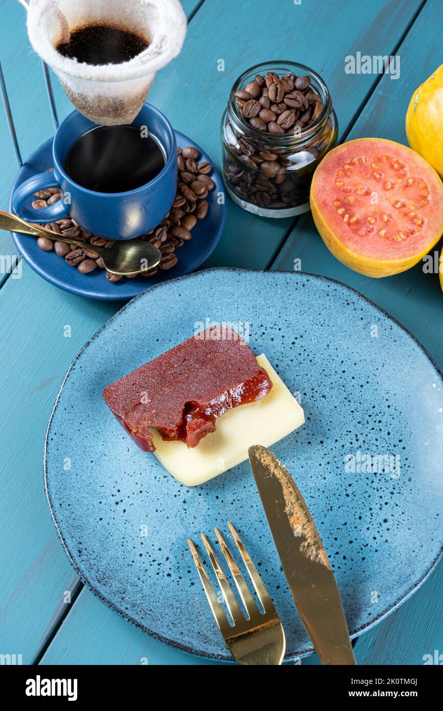 Slices of guava sweet and cheese next to cutlery and beans and cup of ...