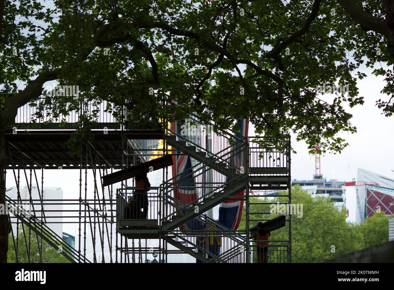 Temporary structures and workers are silhouetted against the Victoria ...