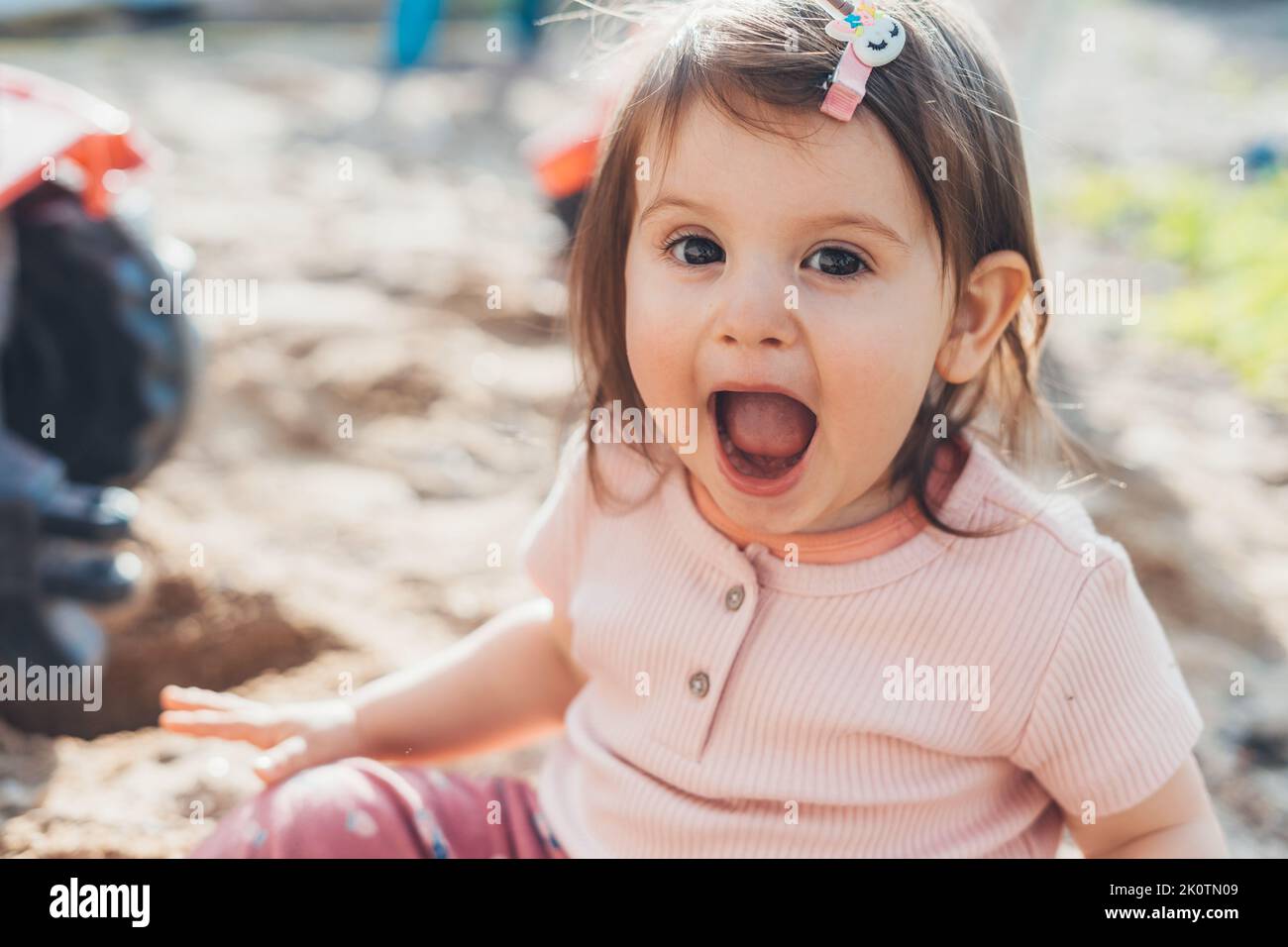 Cute laughing baby girl having fun sitting in garden, positively ...