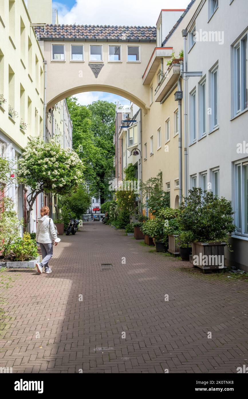 Netherlands, Leiden town. Lady walks between traditional buildings that ...