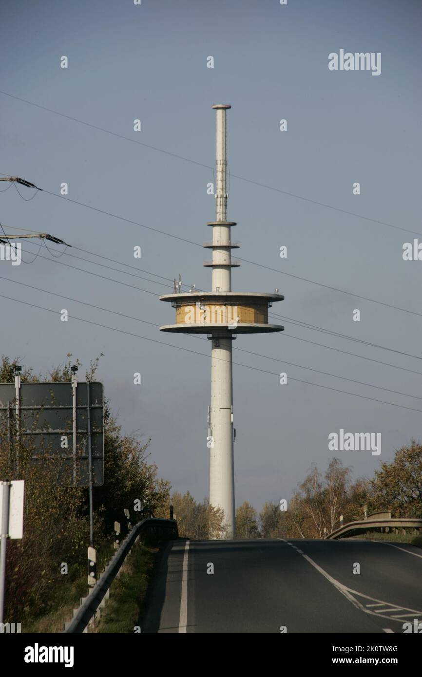 A vertical shot of radio tower at a distance seen from asphalt road ...