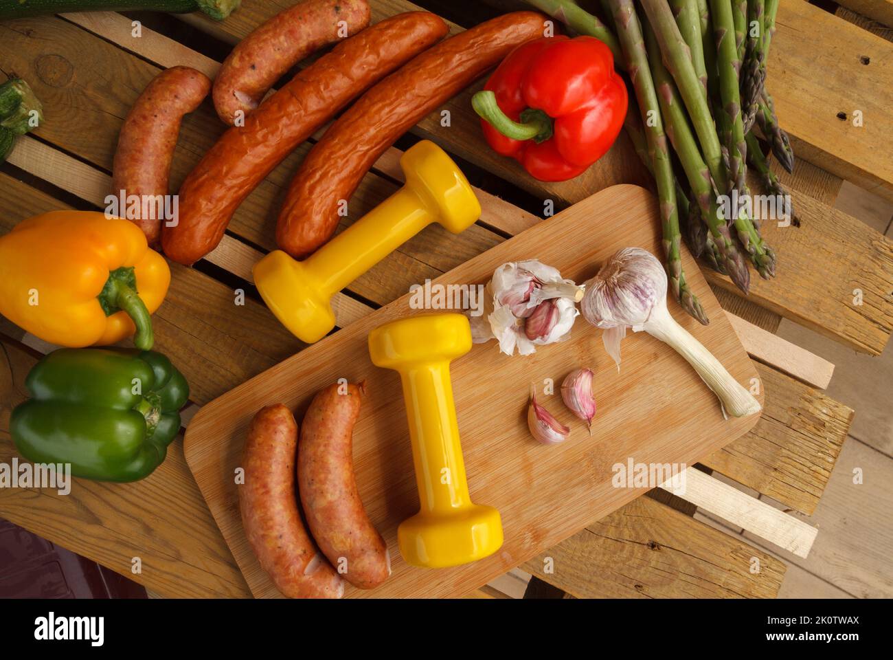 Gym dumbbells with vegetables and sausages prepared for grill cooking ...