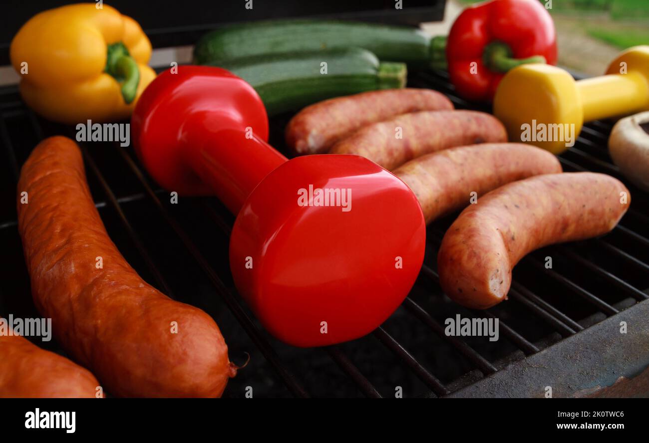 Heavy dumbbells, vegetables and sausages on grill. Fit barbecue party ...