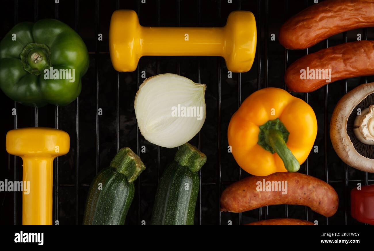 Gym dumbbells, vegetables and sausages on grill. Fit barbecue party ...
