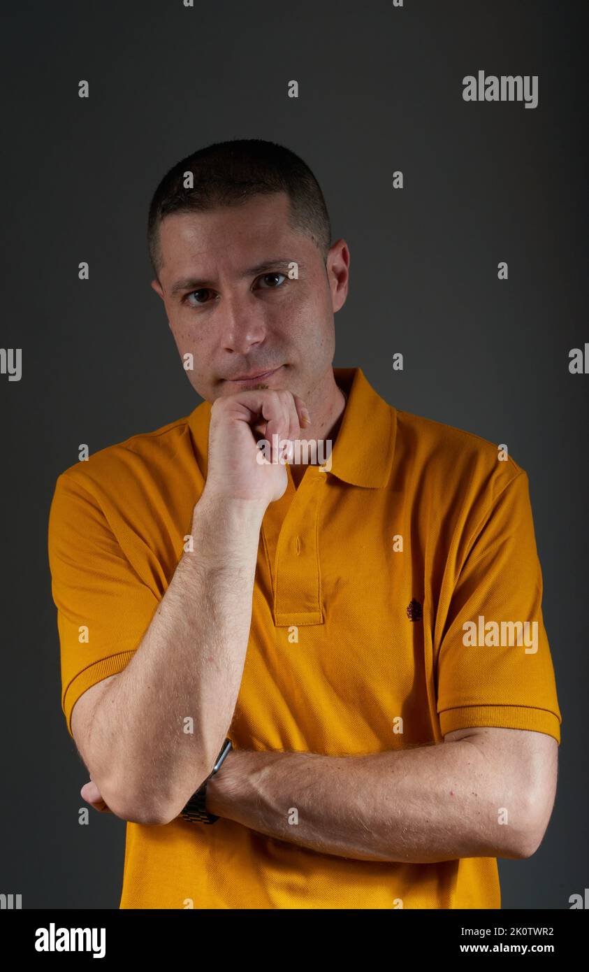 A young and attractive model posing in a studio in a yellow T-shirt ...