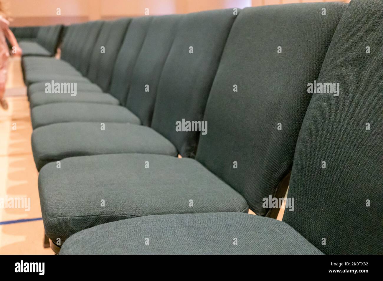 selective focus on a padded seat cushion of a row of chairs in a ...