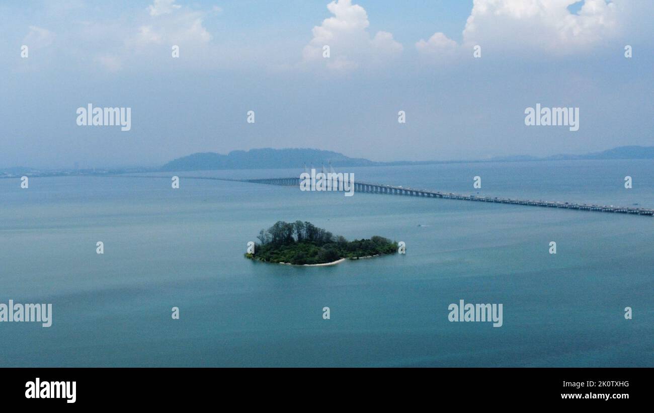 A small green island in the sea with a background of a bridge Stock ...