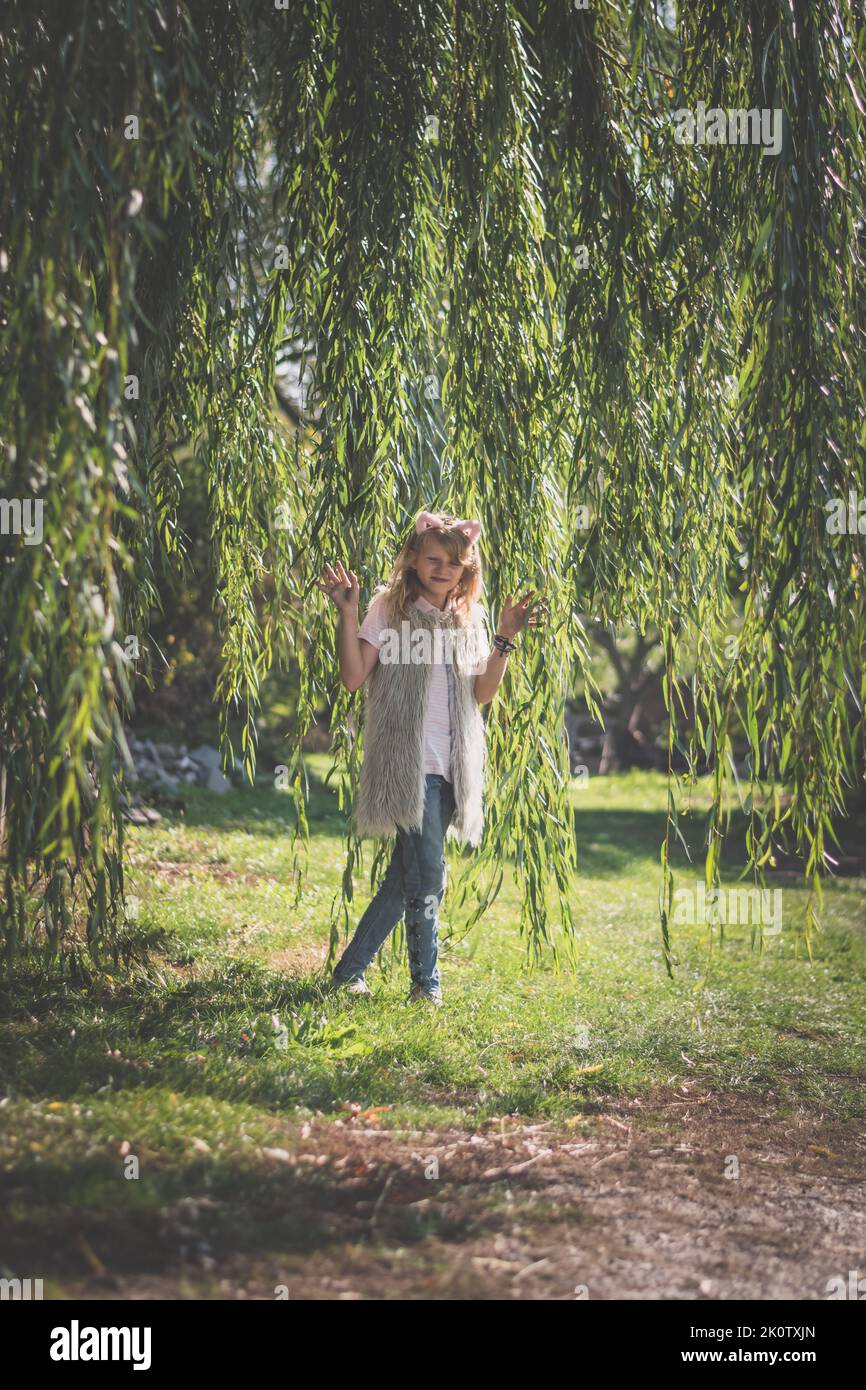 cute teenage girl with long blond hair having fun with willow tree in ...