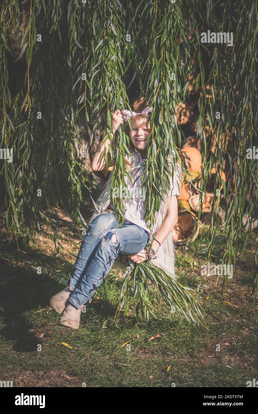 cute teenage girl with long blond hair having fun with willow tree in ...