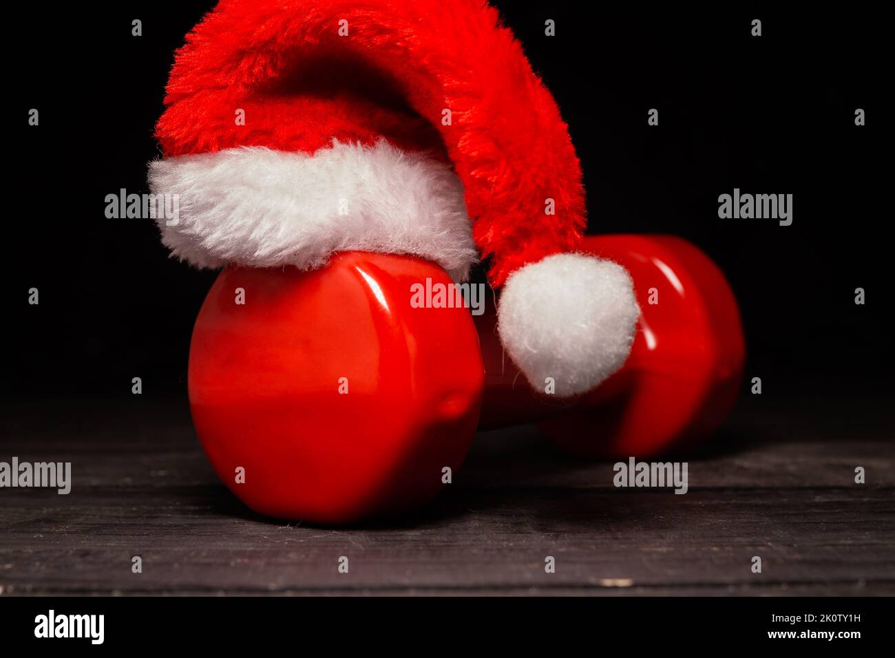 Heavy red dumbbell and Santa Claus hat. Exercise equipment as a ...