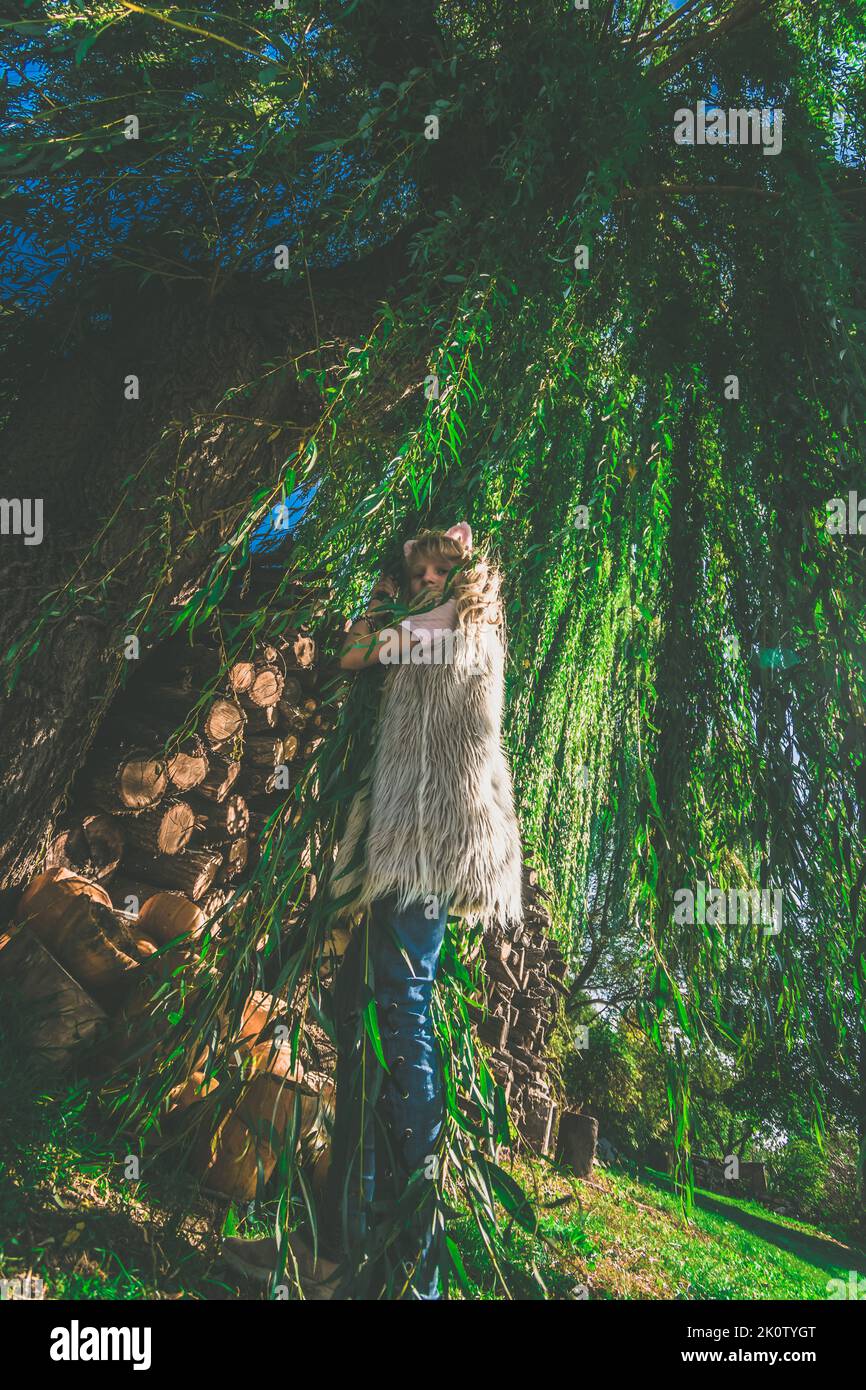 cute teenage girl with long blond hair having fun with willow tree in ...
