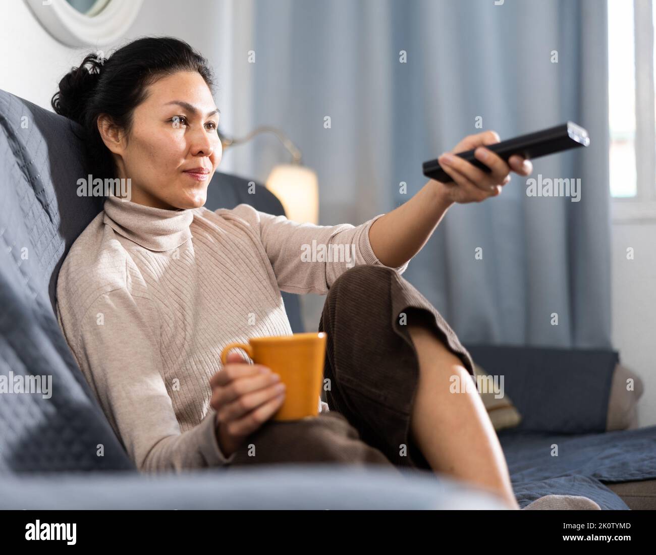 Asian woman watching TV Stock Photo - Alamy