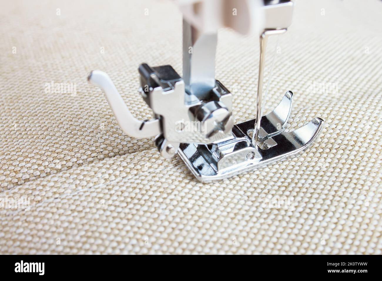 Modern sewing machine presser foot makes a seam on fabric. sewing ...