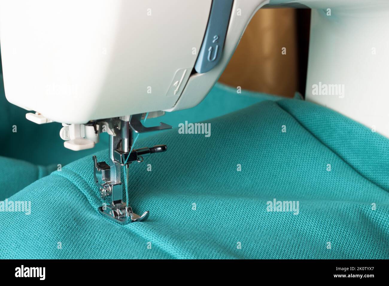 Modern sewing machine working with turquoise fabric. Sewing process ...