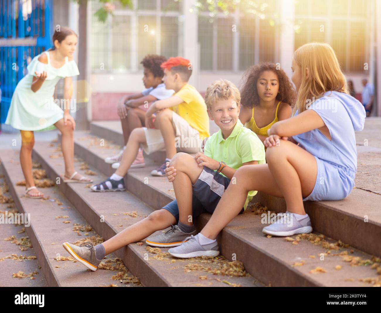 Children talking together while sitting on stairs outdoors Stock Photo ...