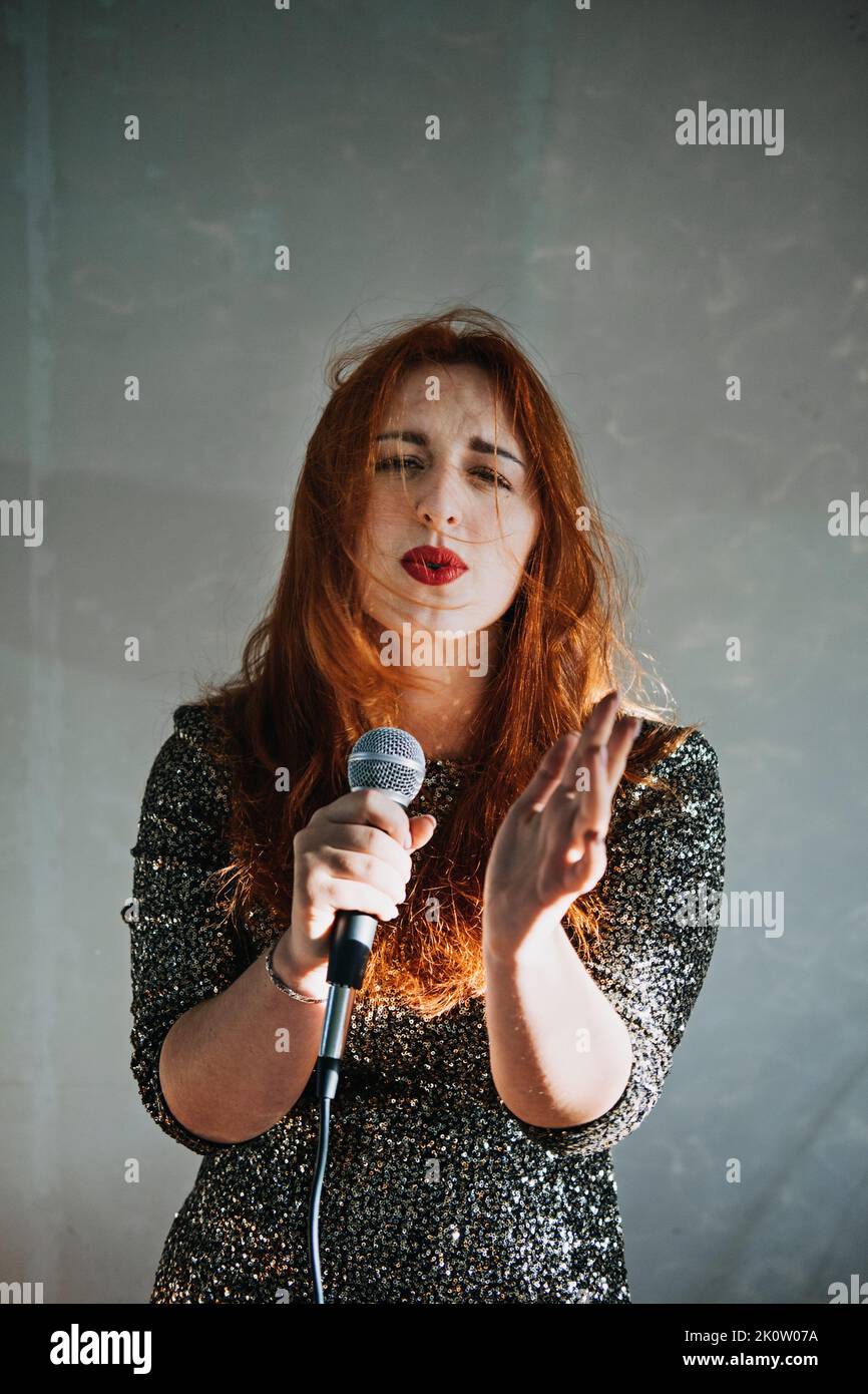Portrait of redhead female singer woman in sparkly evening dress ...