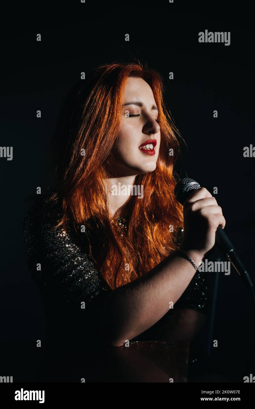 Portrait of redhead female singer woman in sparkly evening dress ...