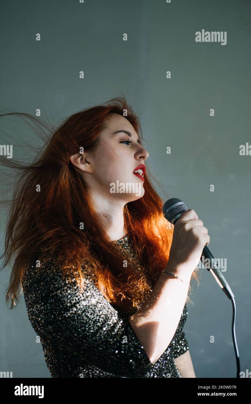 Portrait of redhead female singer woman in sparkly evening dress ...