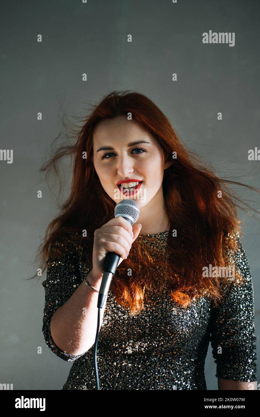 Portrait of redhead female singer woman in sparkly evening dress ...