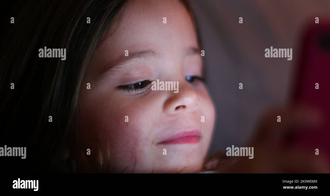 Child girl looking at cellphone screen device. Little girl using ...