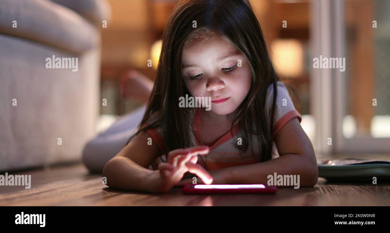 Child watching cellphone screen at night. Blue light from smartphone ...