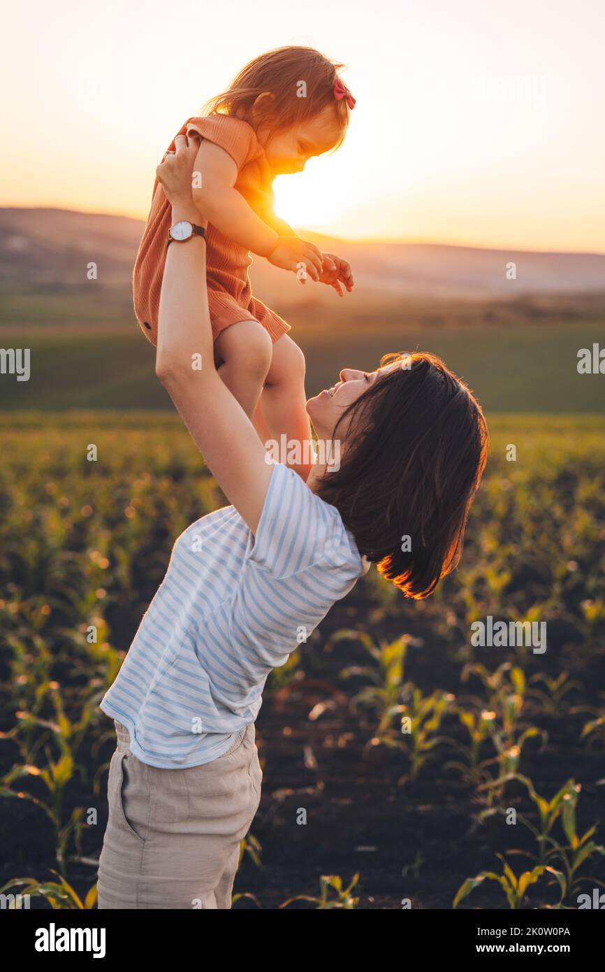 Mother raising her daughter when standing in the middle of the green ...