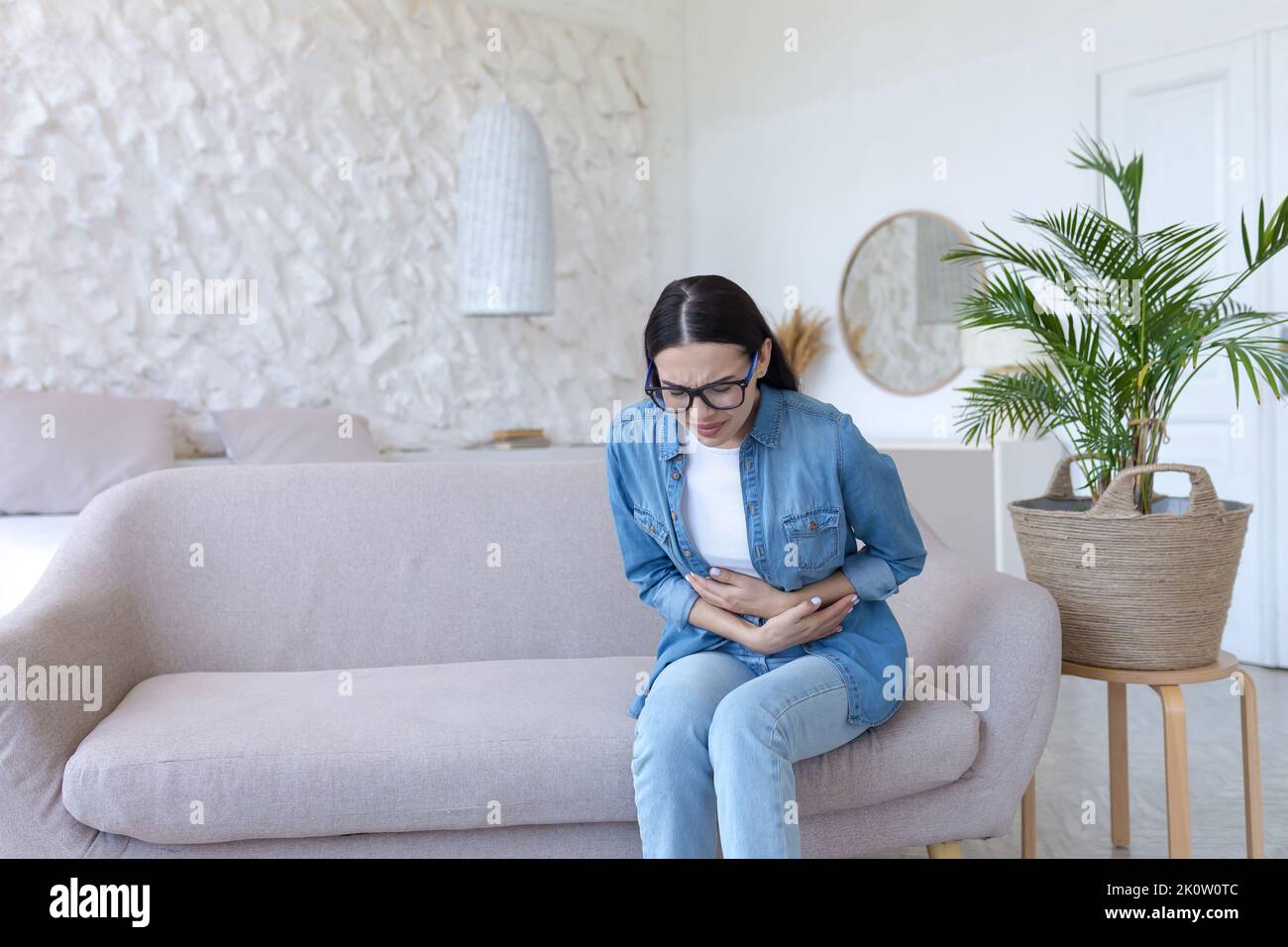 Stomach Ache Young Beautiful Woman In Glasses And Jeans Sitting On The